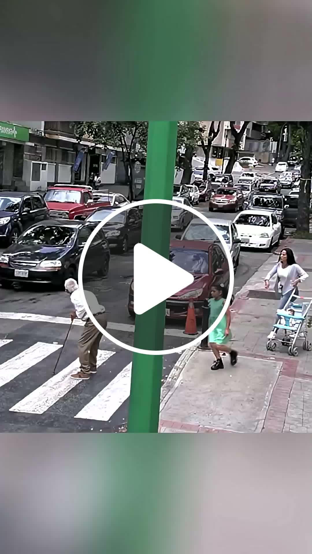 An elderly man, struggling to cross a busy road with his cane, stands ...