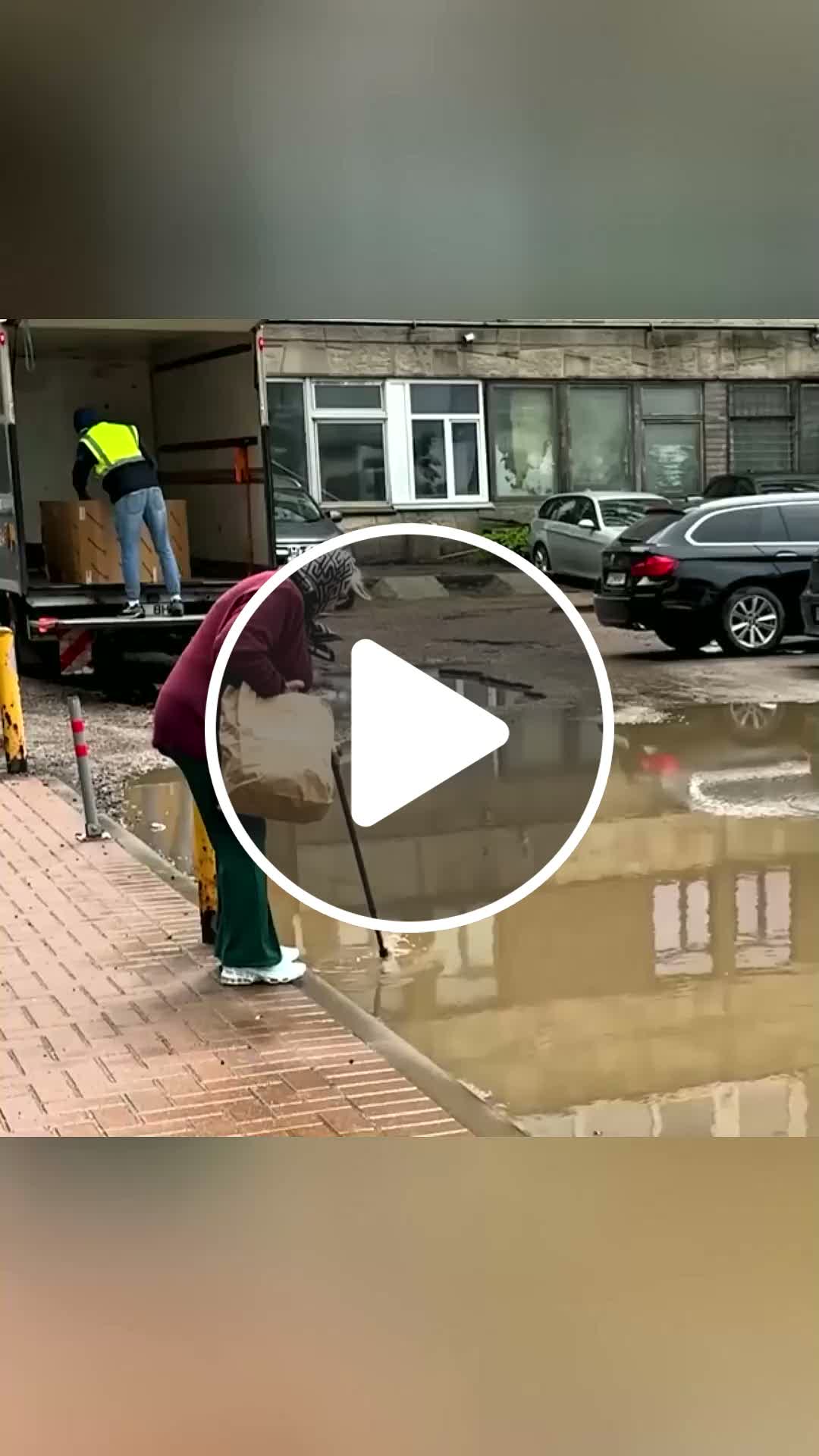 An elderly woman, cane in hand, struggled to cross a flooded road to ...